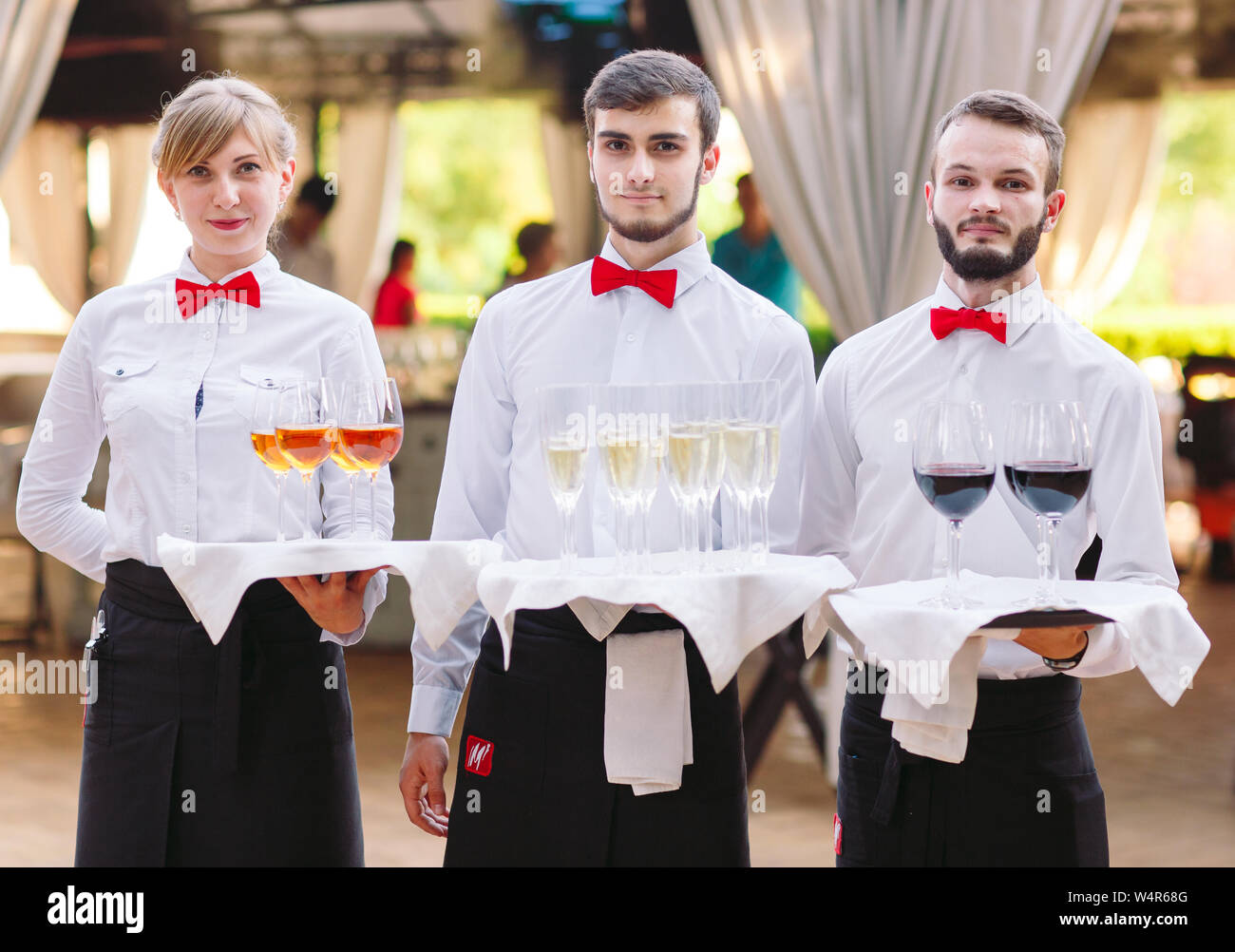 Elegant waiters is holding a tray with a decorated cocktail ready to ...