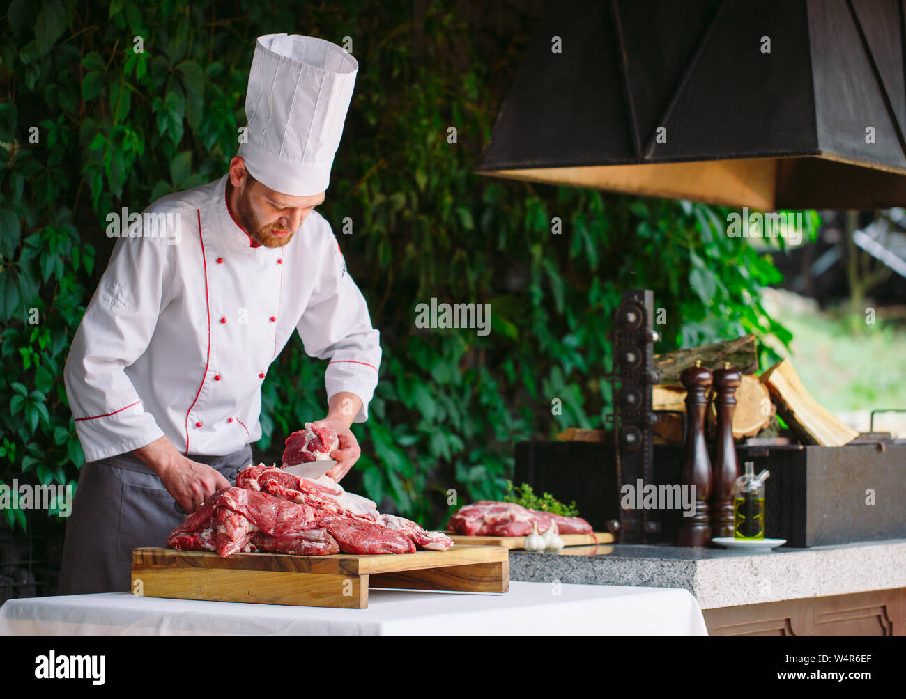 A man cook cuts meat with a knife in a restaurant Stock Photo - Alamy