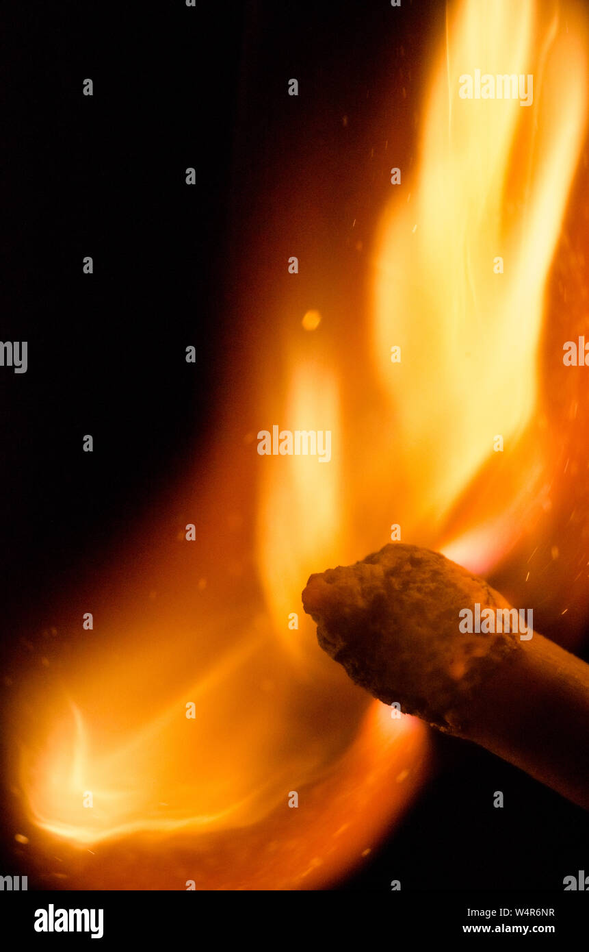 Ignition of matchstick with flames against dark background, still life ...