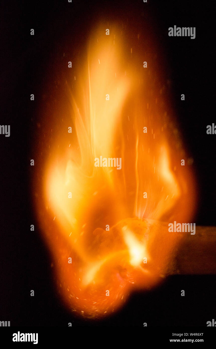 Ignition of matchstick with flames against dark background, still life ...
