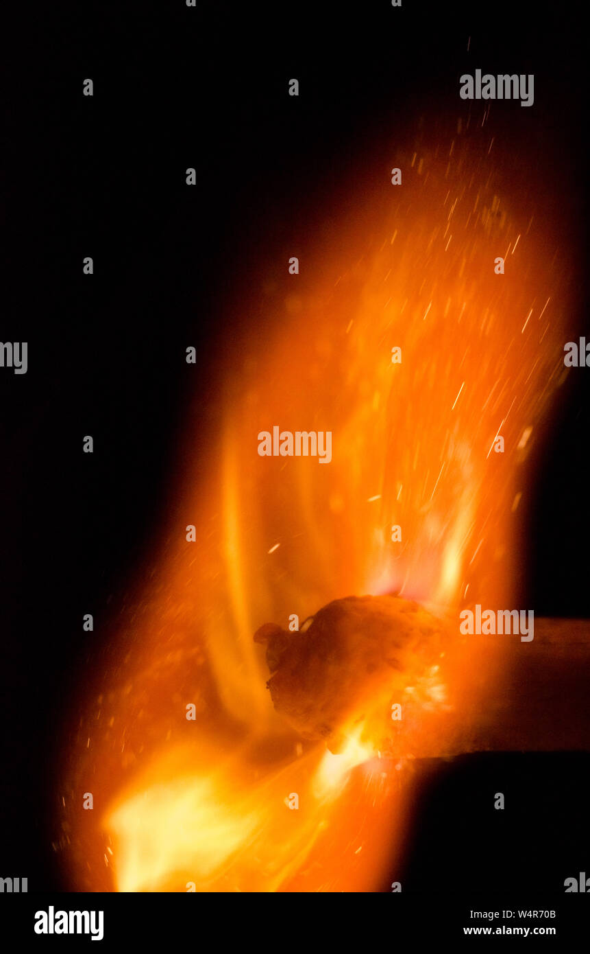 Ignition of matchstick with flames against dark background, still life ...