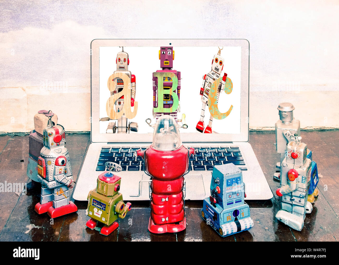 retro robot toys gather around a laptop learning ABC on an old wooden ...