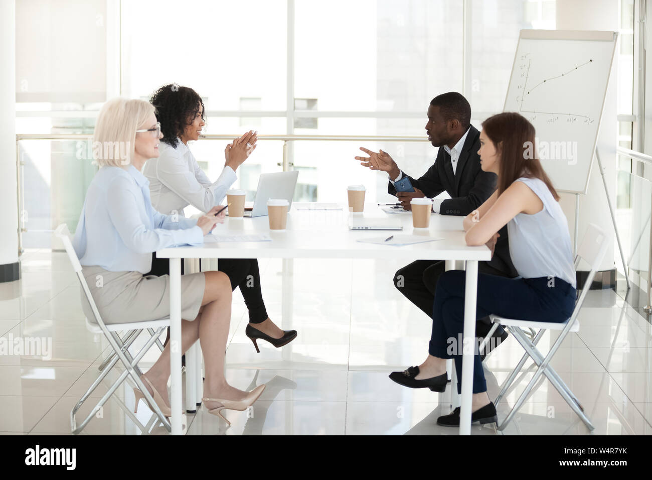Diverse employees sit at table, discussing project in boardroom Stock ...