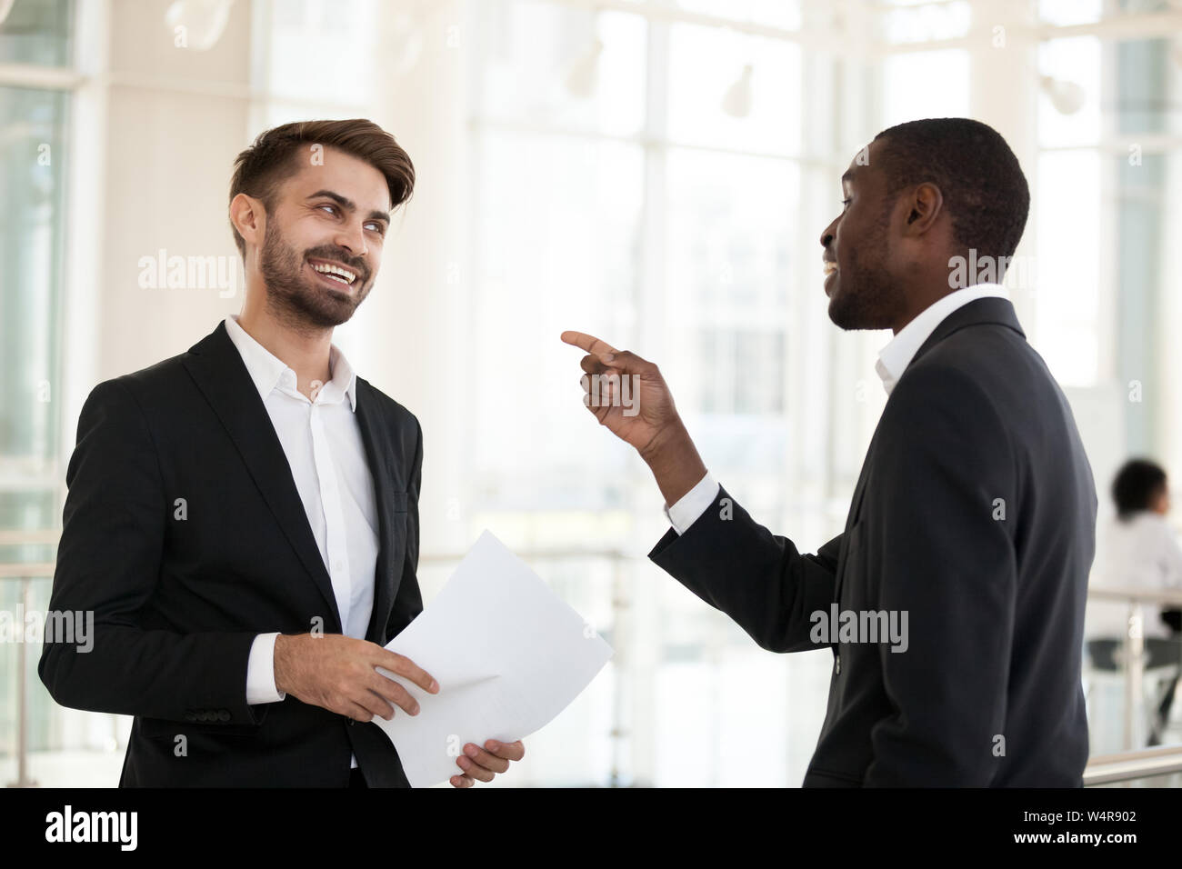 Diverse employees laughing at joke during break in office Stock Photo ...