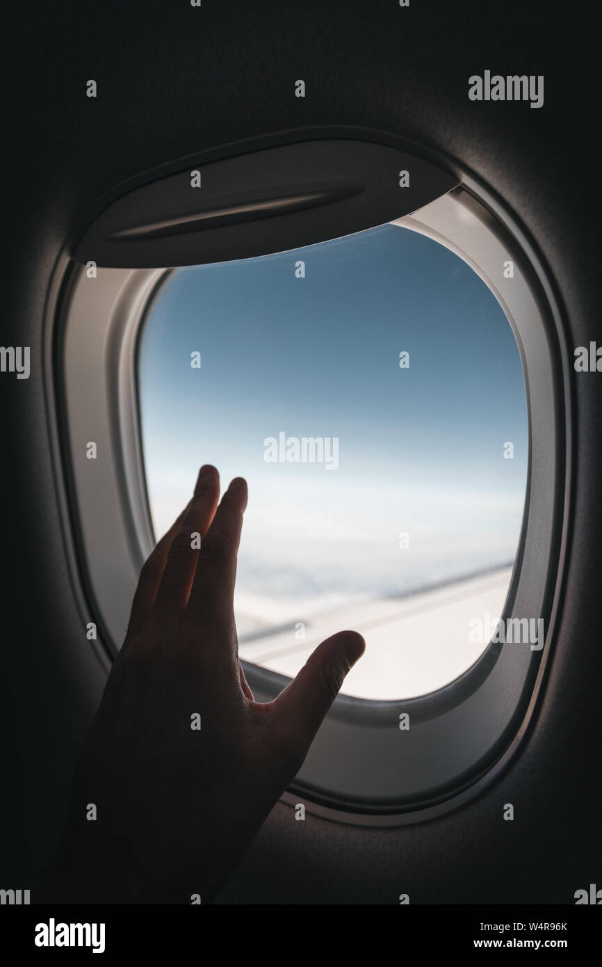 Porthole window in the plane with a man's hand during the flight Stock ...
