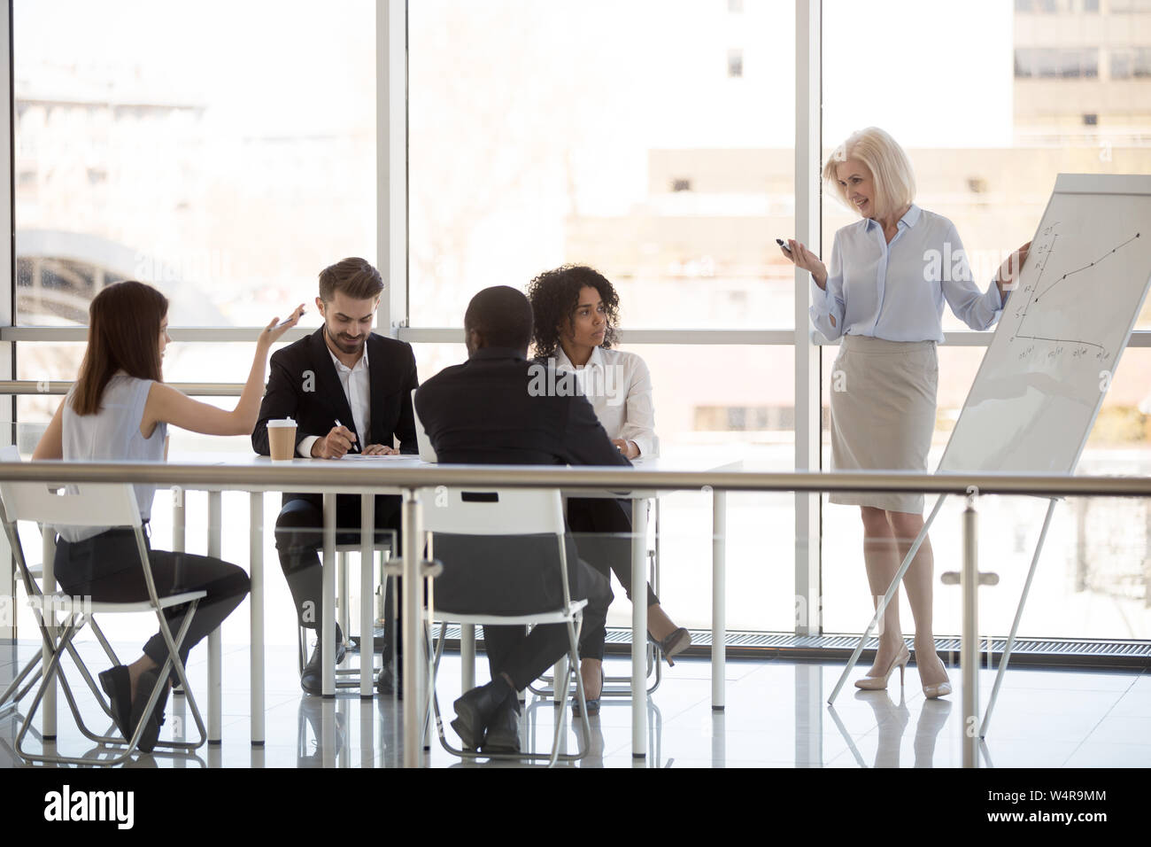 Female employee ask question to middle-aged coach at company meeting ...