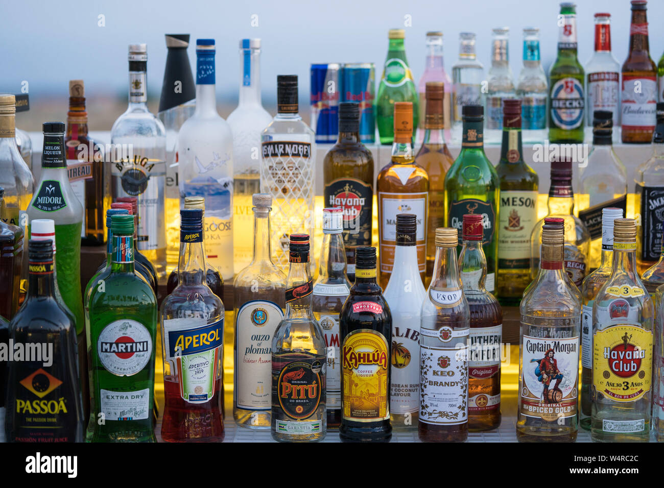 Various colourful alcoholic drink bottles lined up on a shelfs at a pub ...