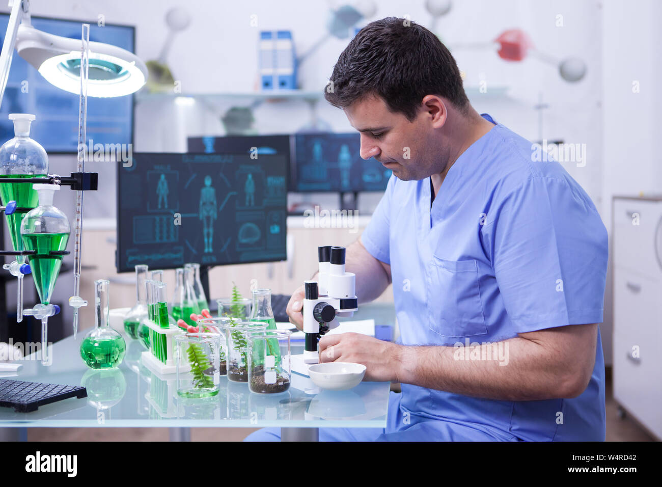 Young microbiologist working on his microscope in a research lab ...