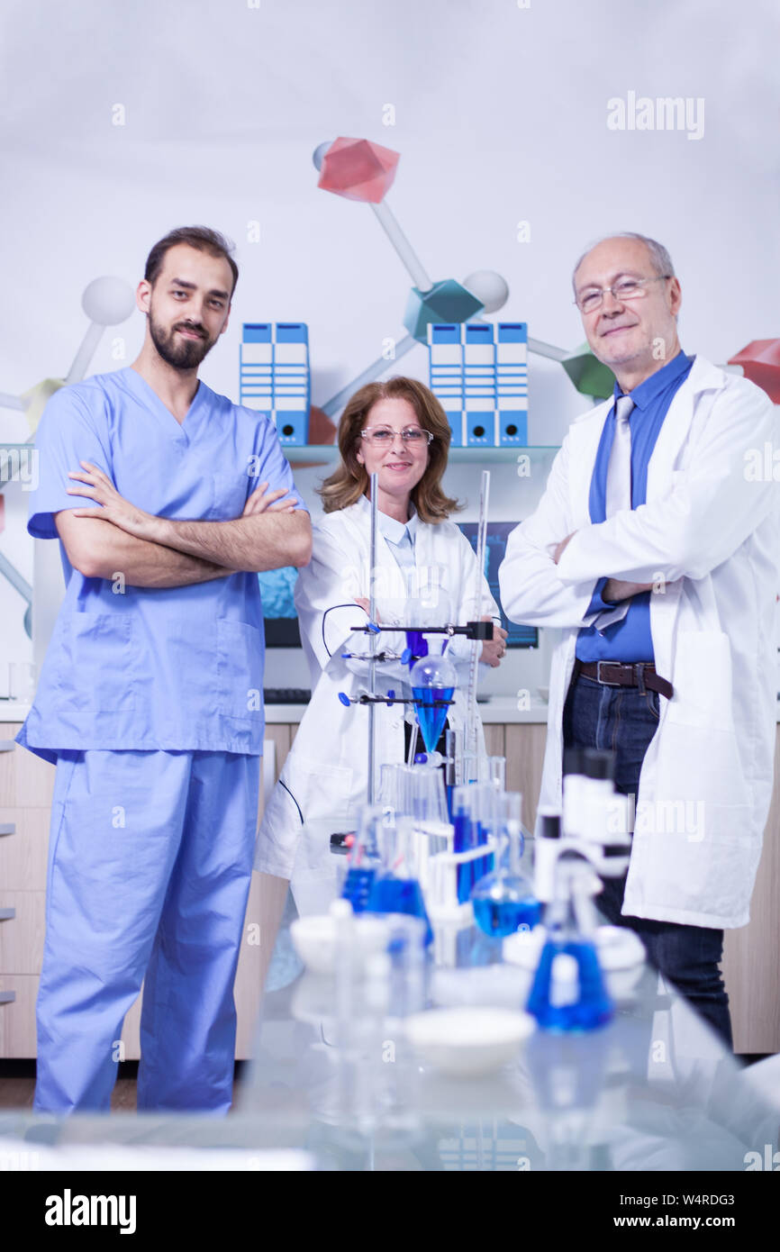 Female scientist smiling to the camera with her colleagues by her side ...