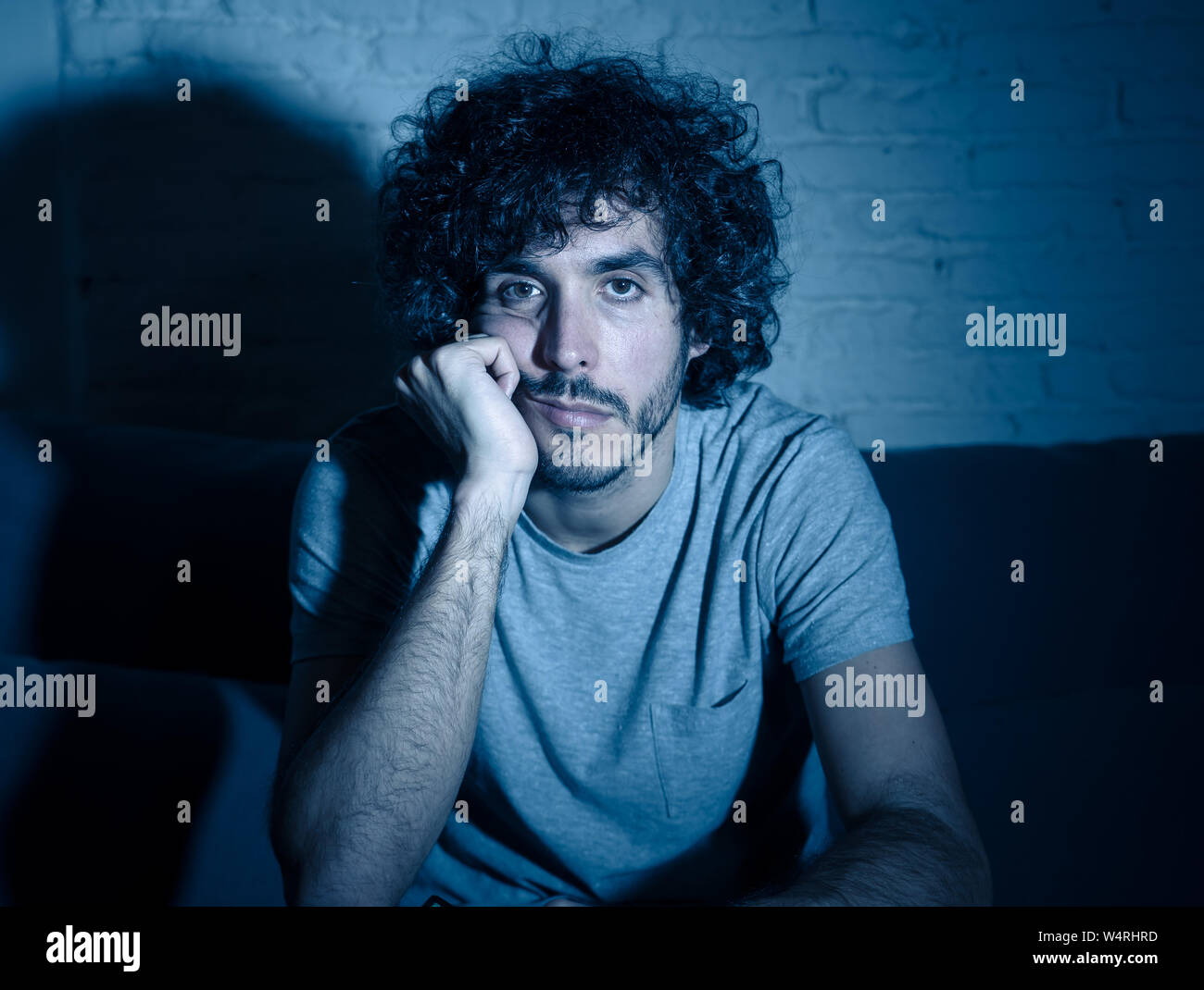 Young bored man on couch using TV remote control zapping for another ...