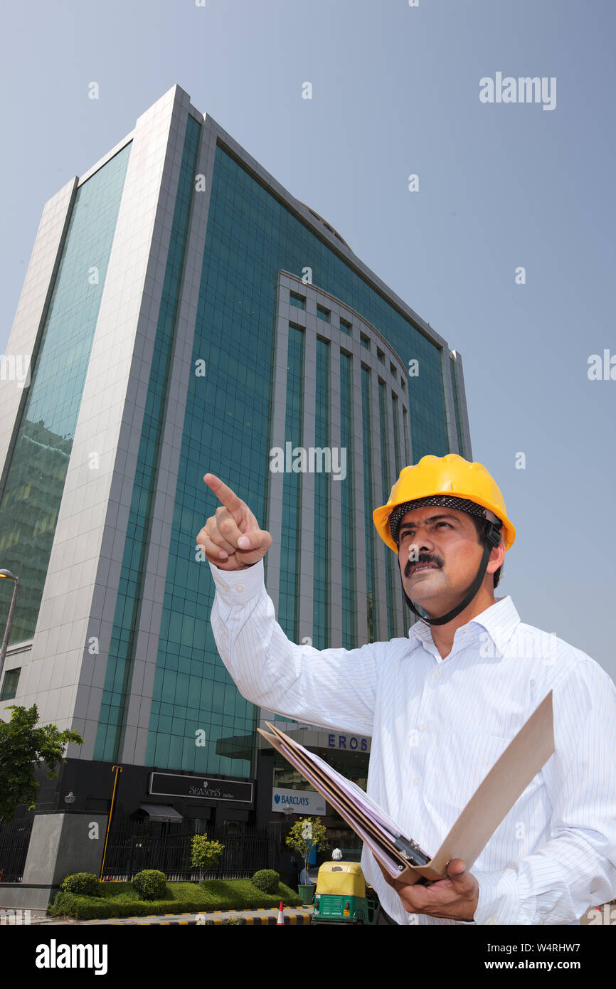Engineer pointing with an office building in the background Stock Photo ...