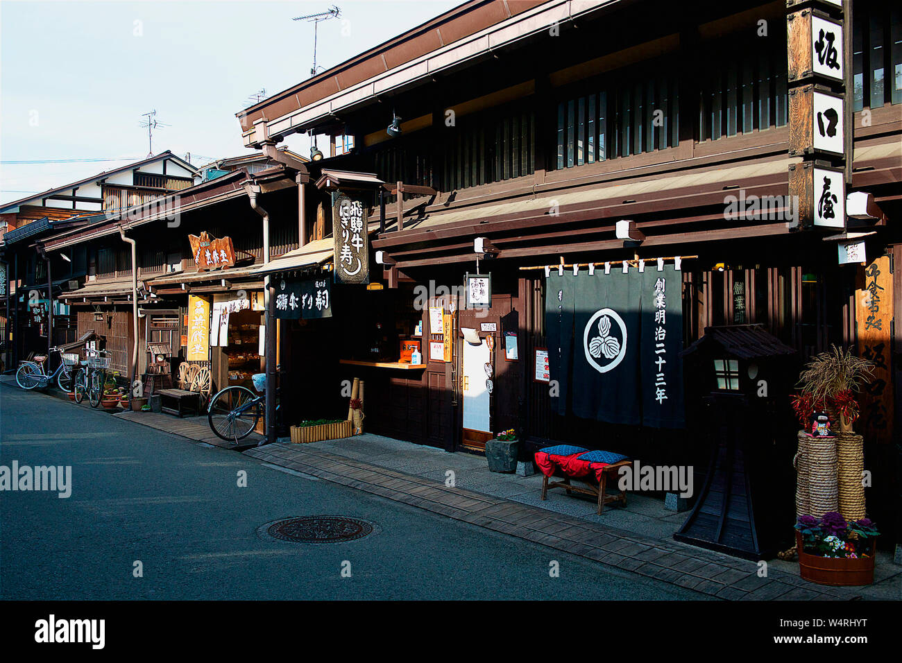 Shopping street with small shops in wooden buildings and bicycles, Hida ...