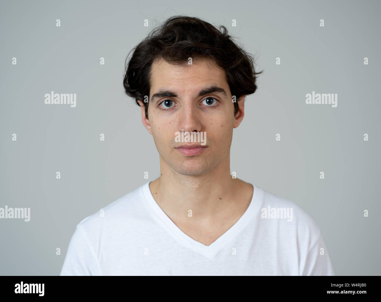 Close up headshot of young latin man with natural and serious face and ...