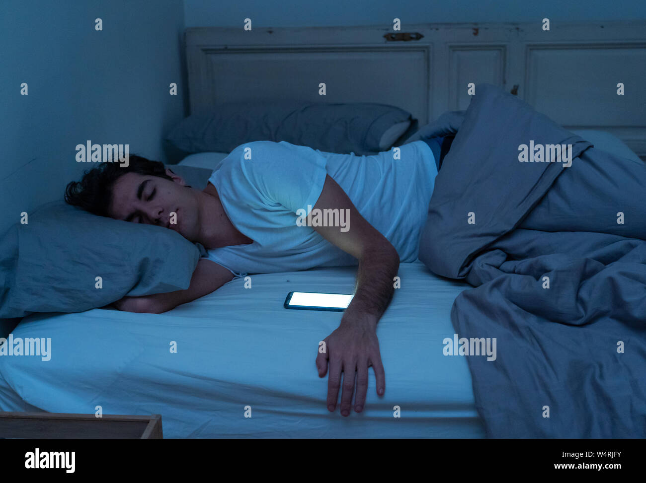 Addicted to social media young man falling asleep with smart mobile ...