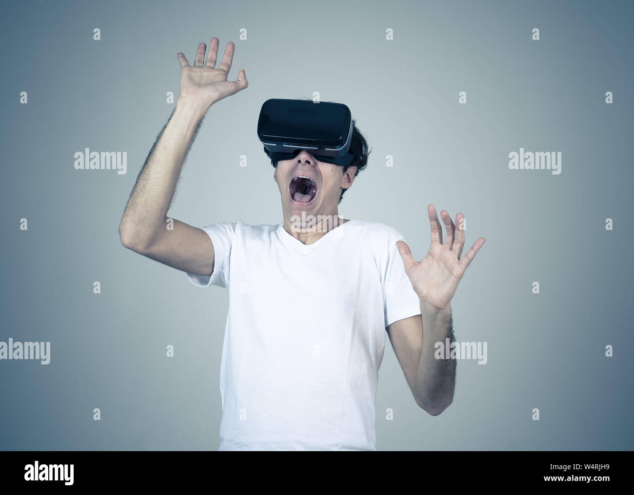 Young man using virtual reality goggles feeling excited and shock ...