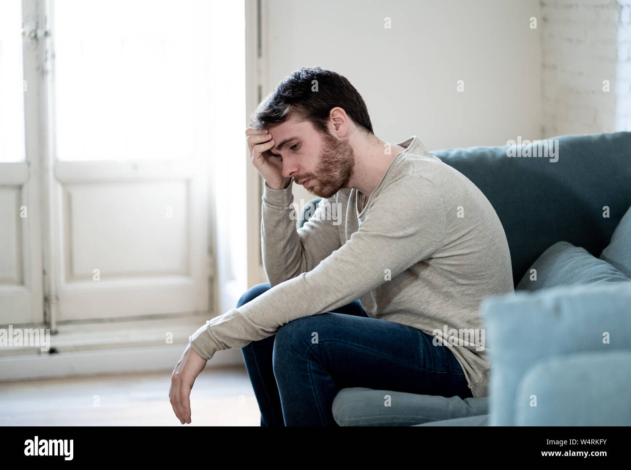 Unhappy depressed caucasian male sitting and lying in living room couch ...