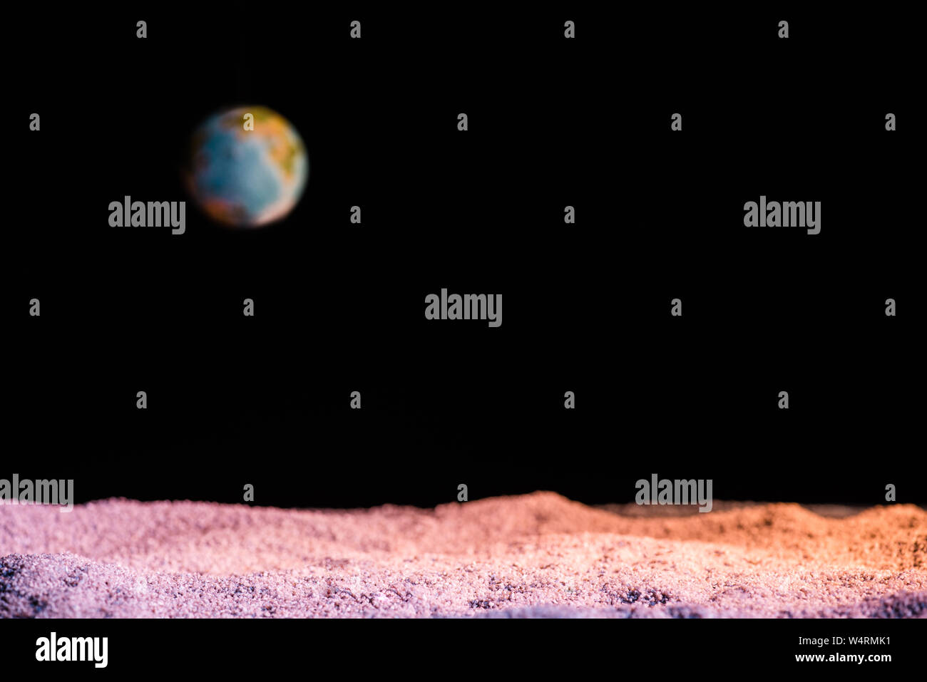 selective focus of textured ground with blurred planet Earth in space ...