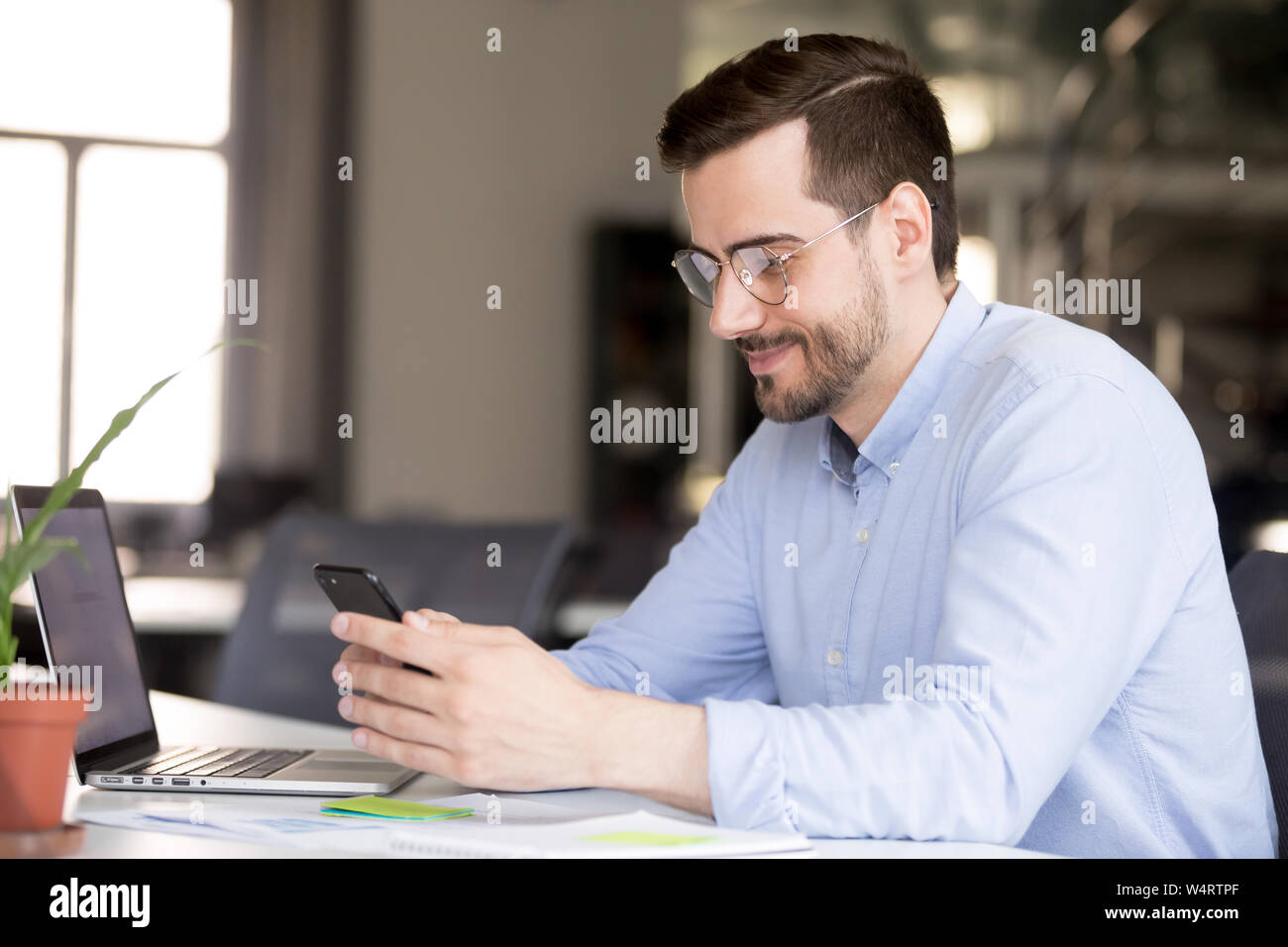 Satisfied businessman using mobile phone at workplace Stock Photo - Alamy