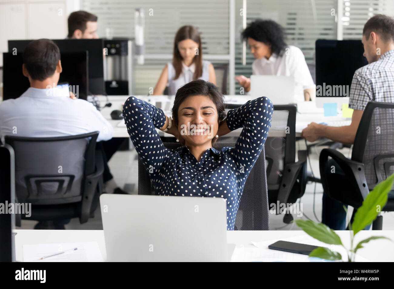 Smiling Indian female employee relaxing leaning back at workplace Stock ...