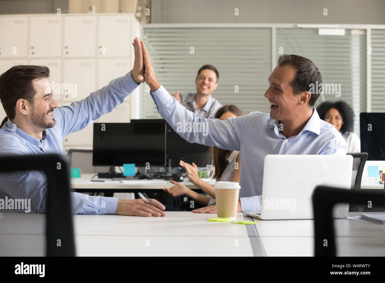Happy excited male colleagues giving high five at work Stock Photo - Alamy