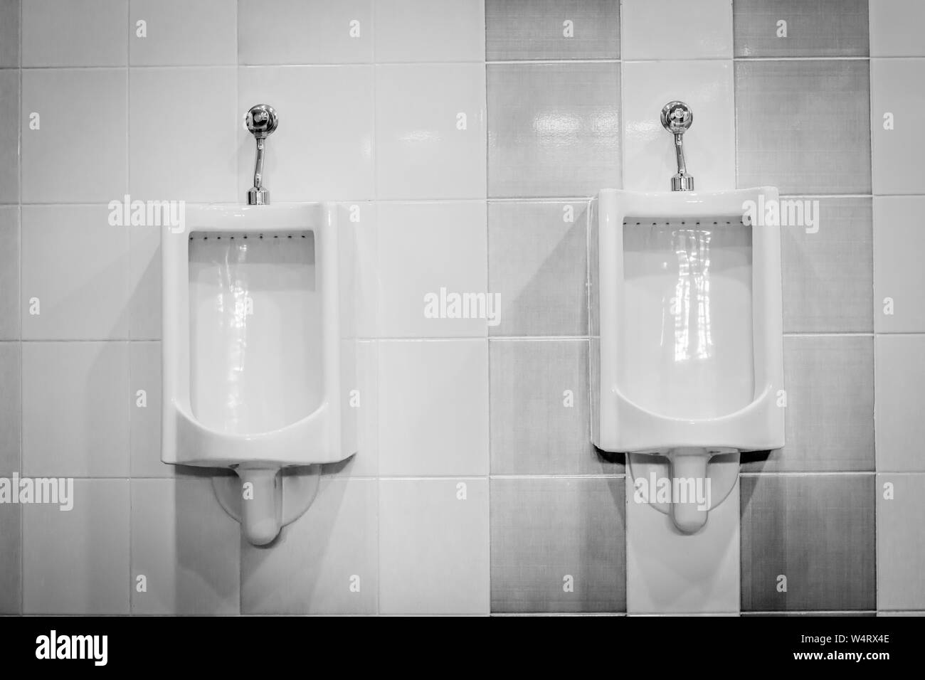 Urinals in the bathroom on the background wall tiles Stock Photo - Alamy