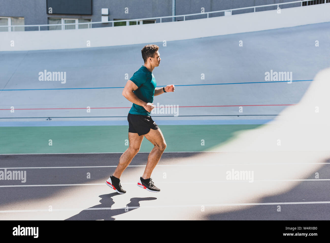 side view of mixed race sportsman running on track at stadium Stock ...