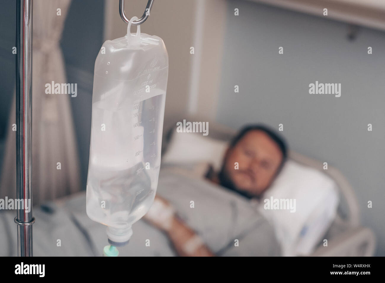 Male lying on a hospital bed. Dropper in a man's hand in a hospital ...