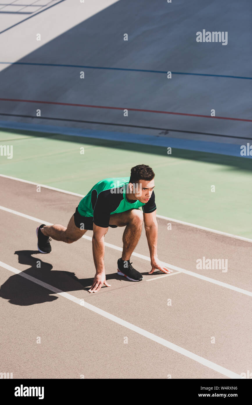 mixed race sportsman preparing to run at stadium Stock Photo - Alamy