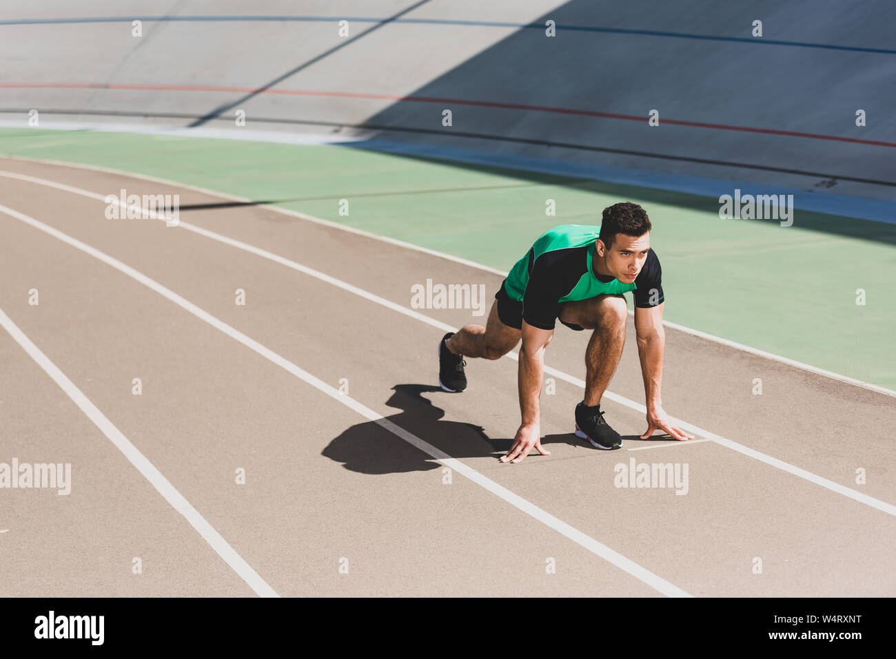 mixed race sportsman preparing to run at stadium Stock Photo - Alamy