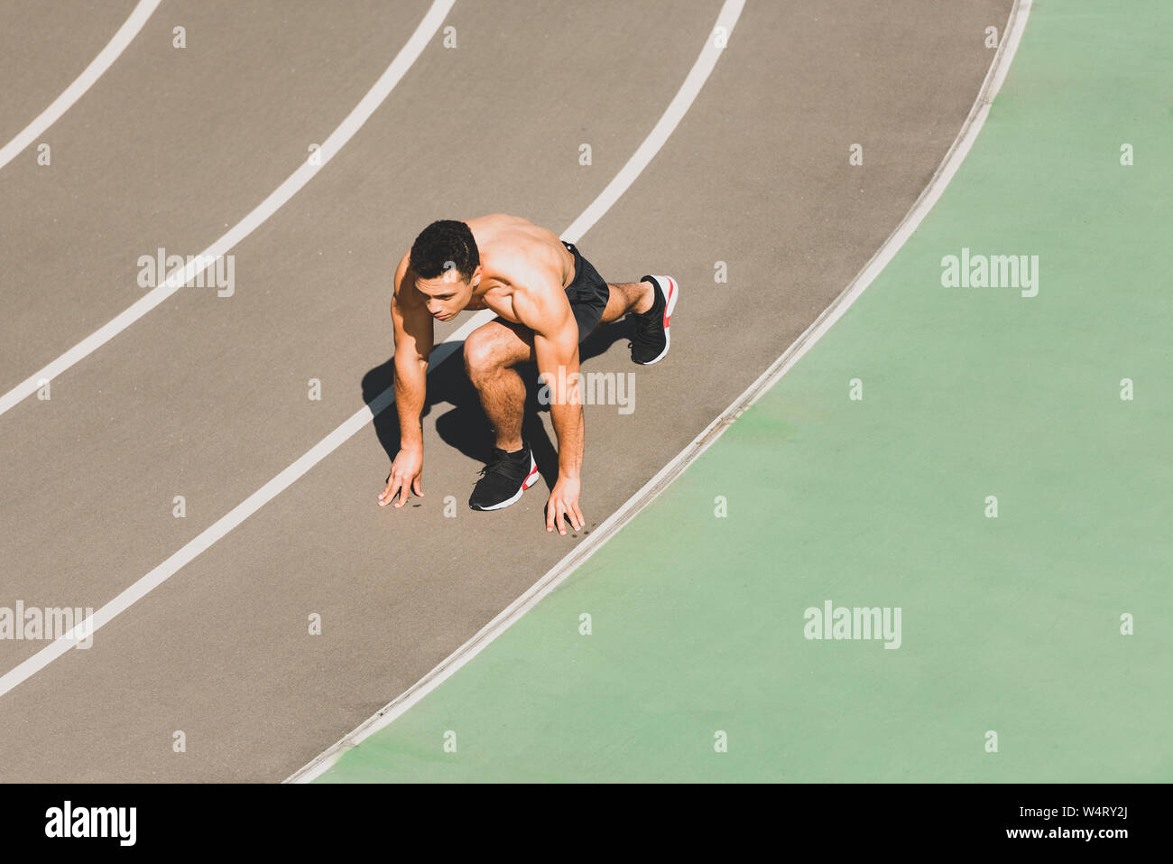 mixed race sportsman preparing to run at stadium Stock Photo - Alamy