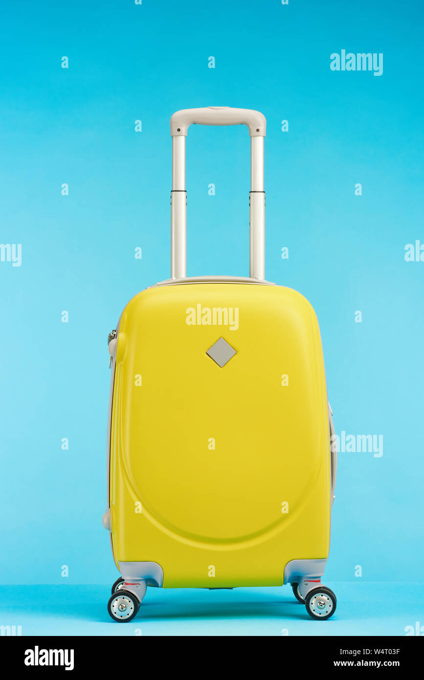 yellow colorful suitcase with handle on wheels on blue background Stock ...