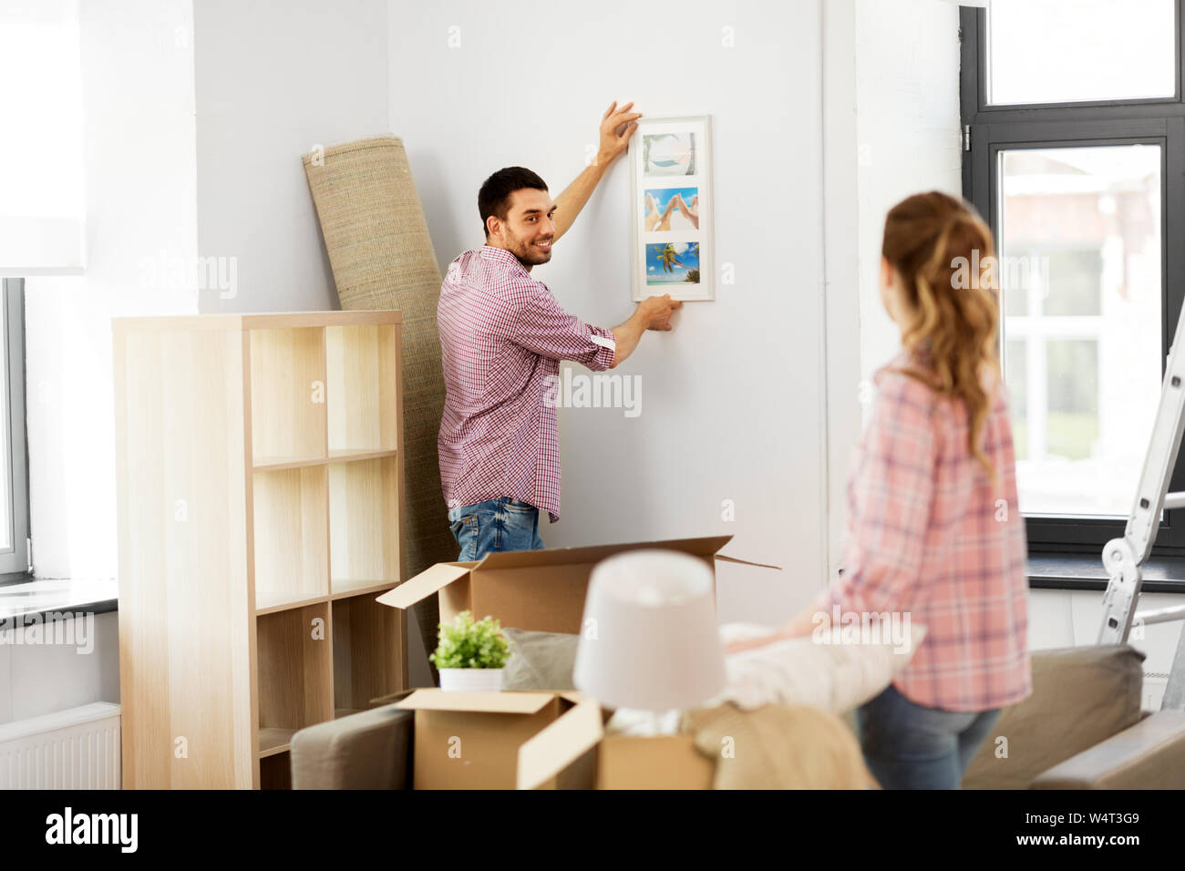 happy couple moving to new home and hanging photo Stock Photo - Alamy