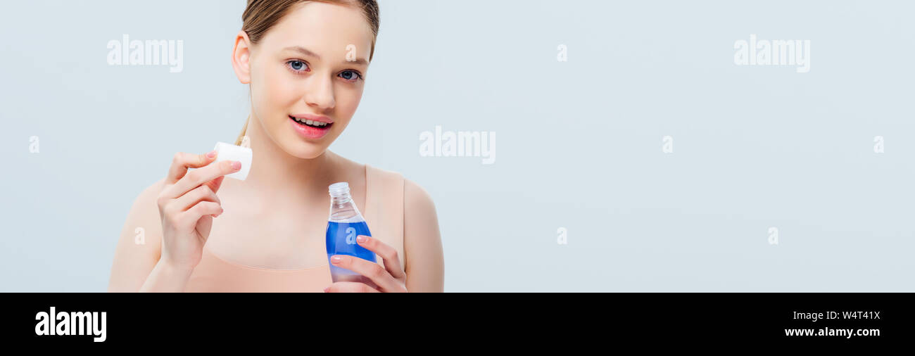 smiling teenage girl holding opened bottle with blue lotion isolated on ...