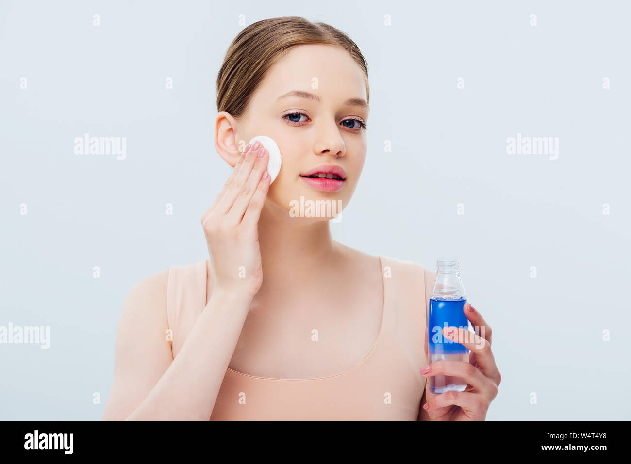 pretty teenage girl applying lotion on face with cotton pad isolated on ...