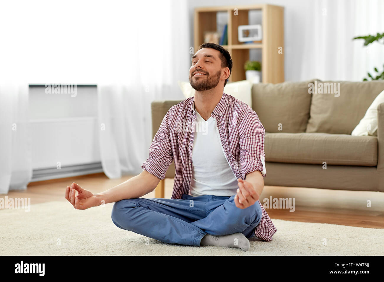 man meditating in lotus pose at home Stock Photo - Alamy