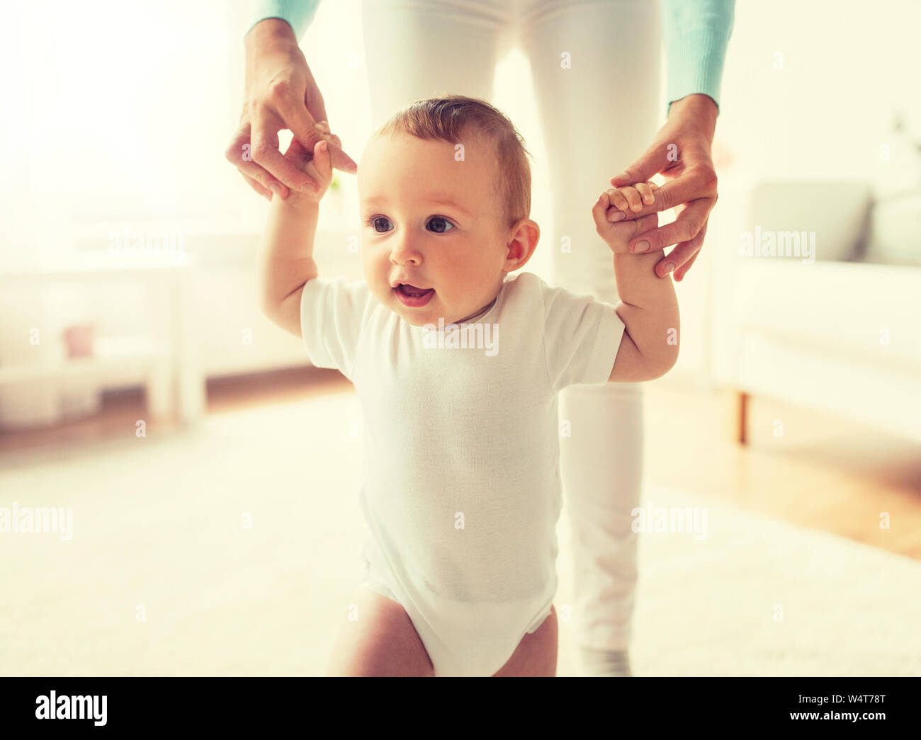 happy baby learning to walk with mother help Stock Photo - Alamy