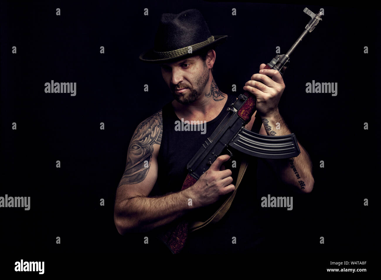 low key portrait of gangster with hat and maschine gun in the darkness ...