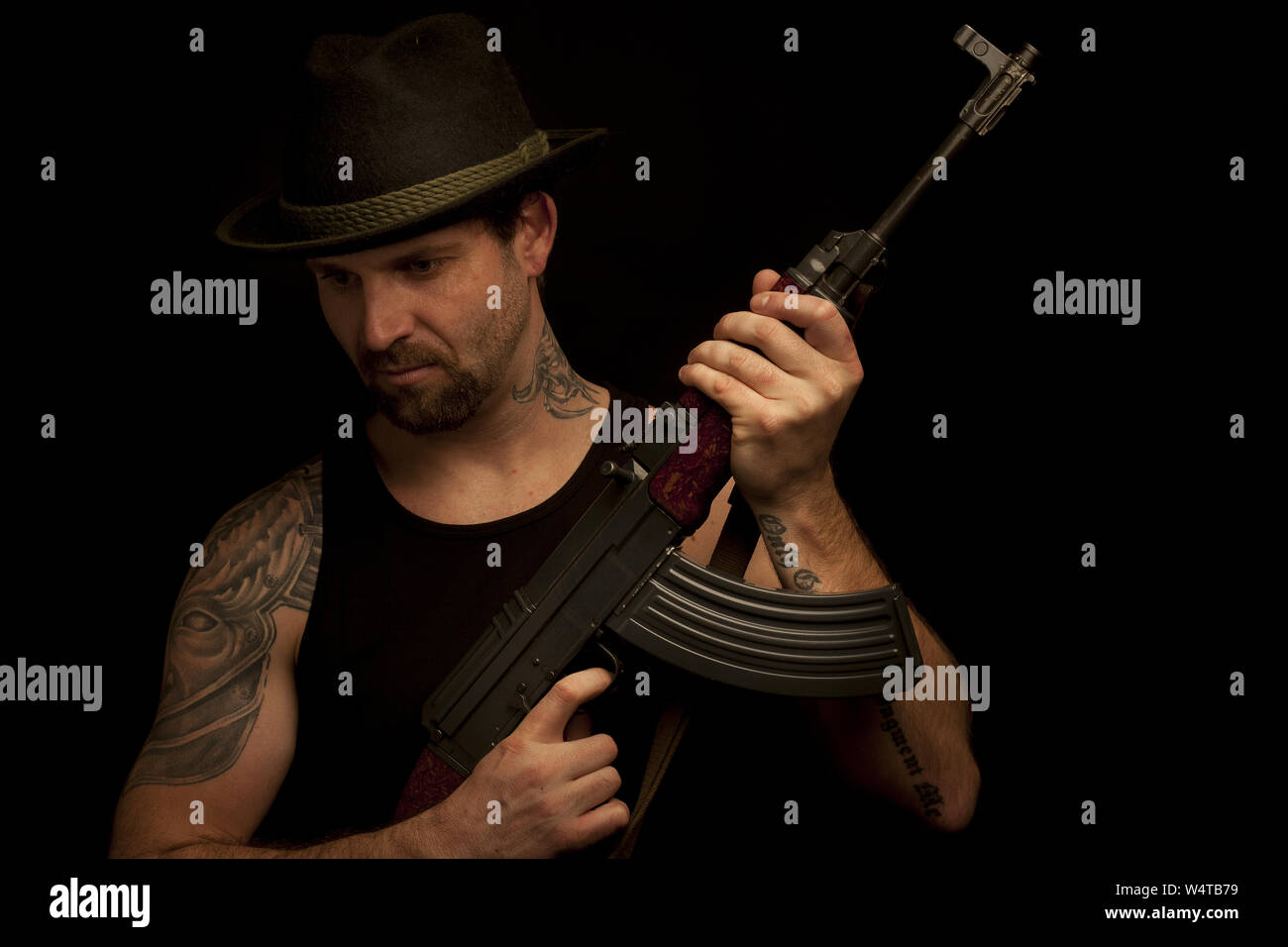low key portrait of gangster with hat and maschine gun in the darkness ...