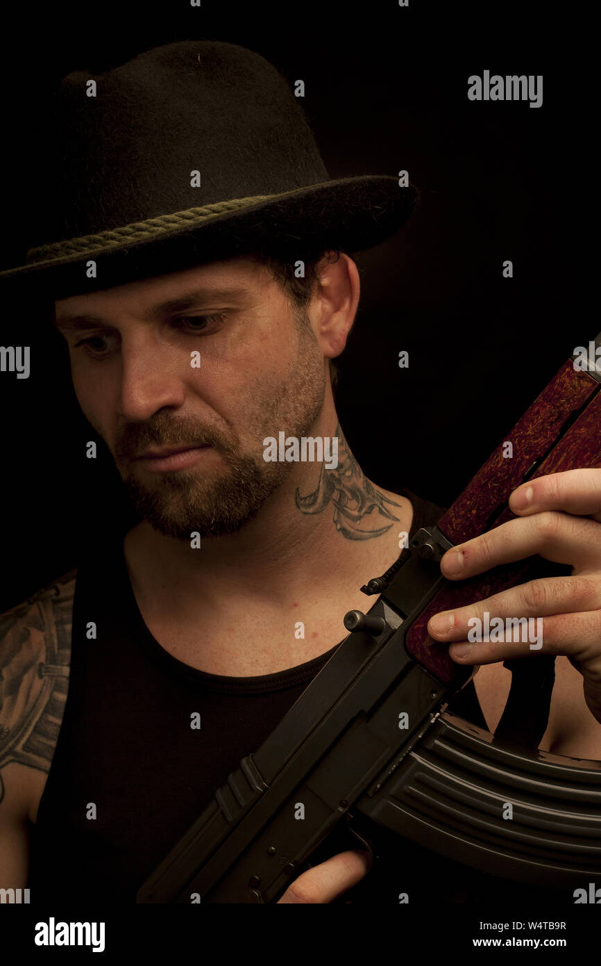 low key portrait of gangster with hat and maschine gun in the darkness ...