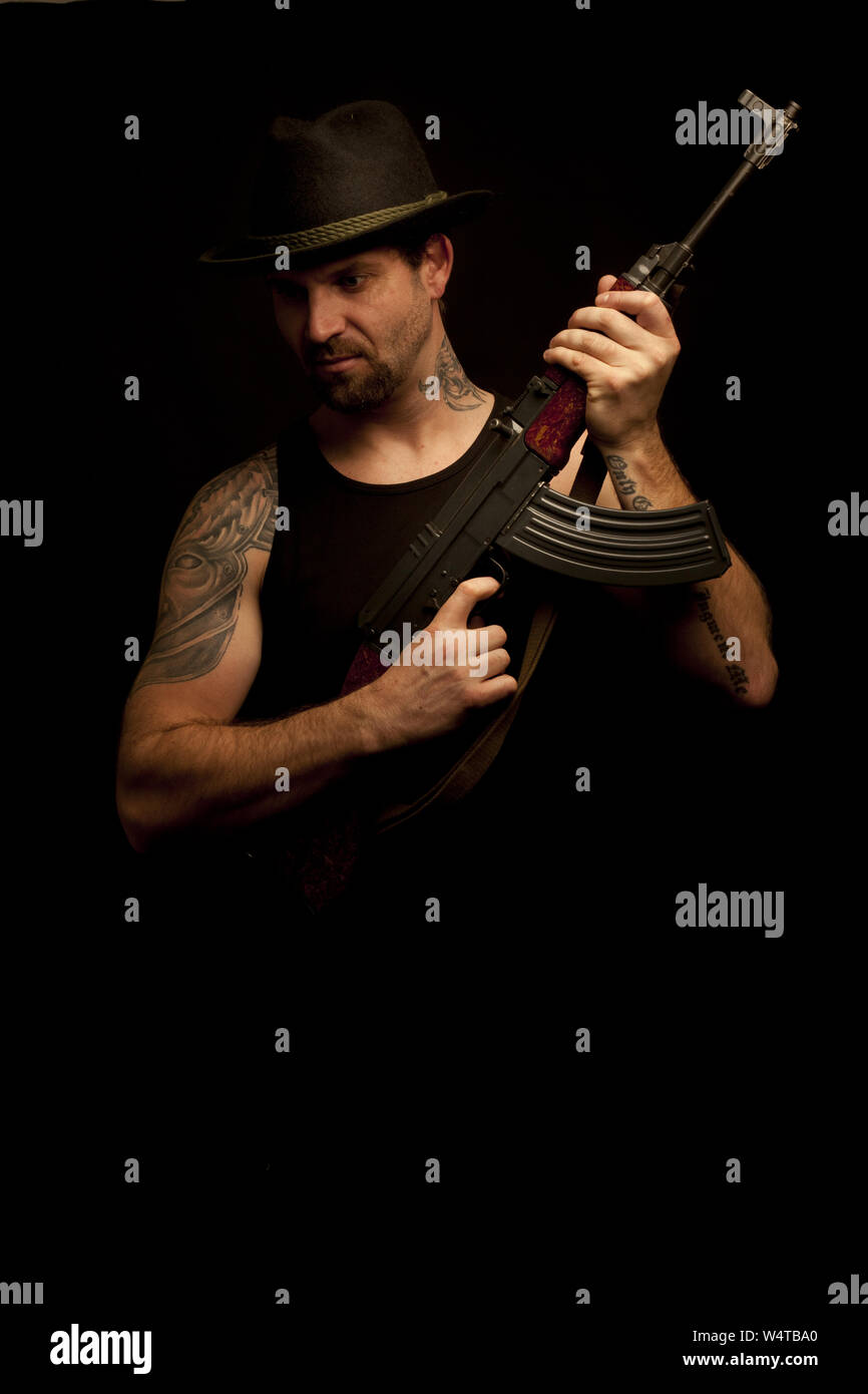 low key portrait of gangster with hat and maschine gun in the darkness ...