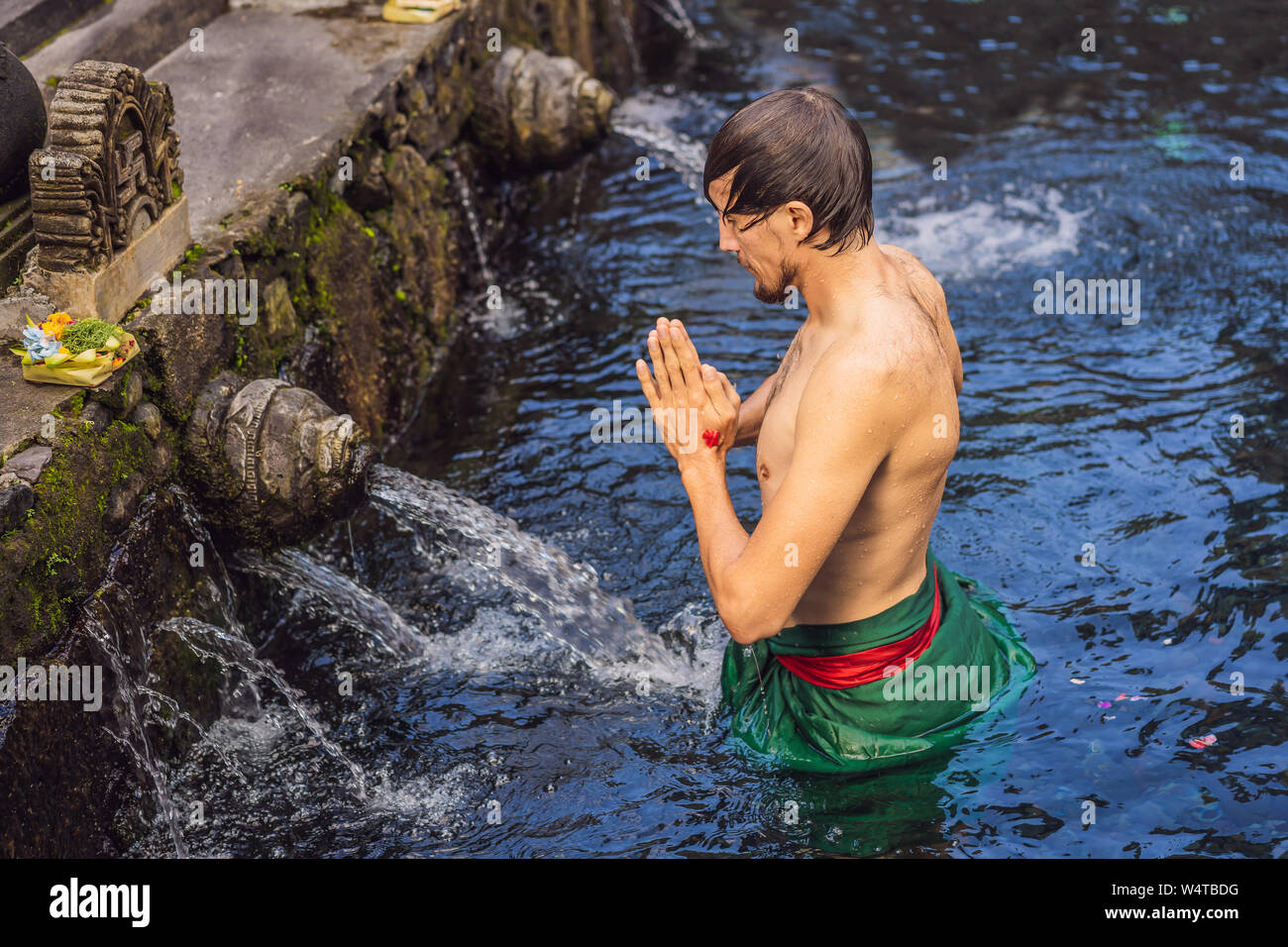 Man in holy spring water temple in bali. The temple compound consists ...
