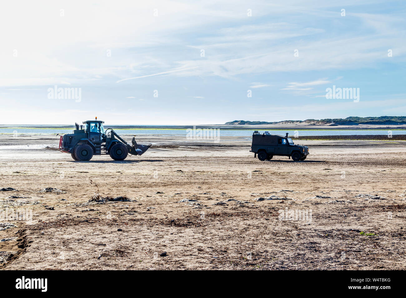 A JCB digger and Land Rover on the sandy beach at Instow, Devon, UK ...