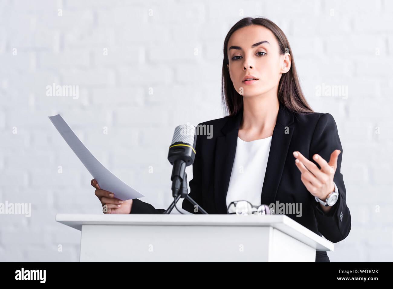 confident lecturer gesturing while speaking into microphone on podium ...