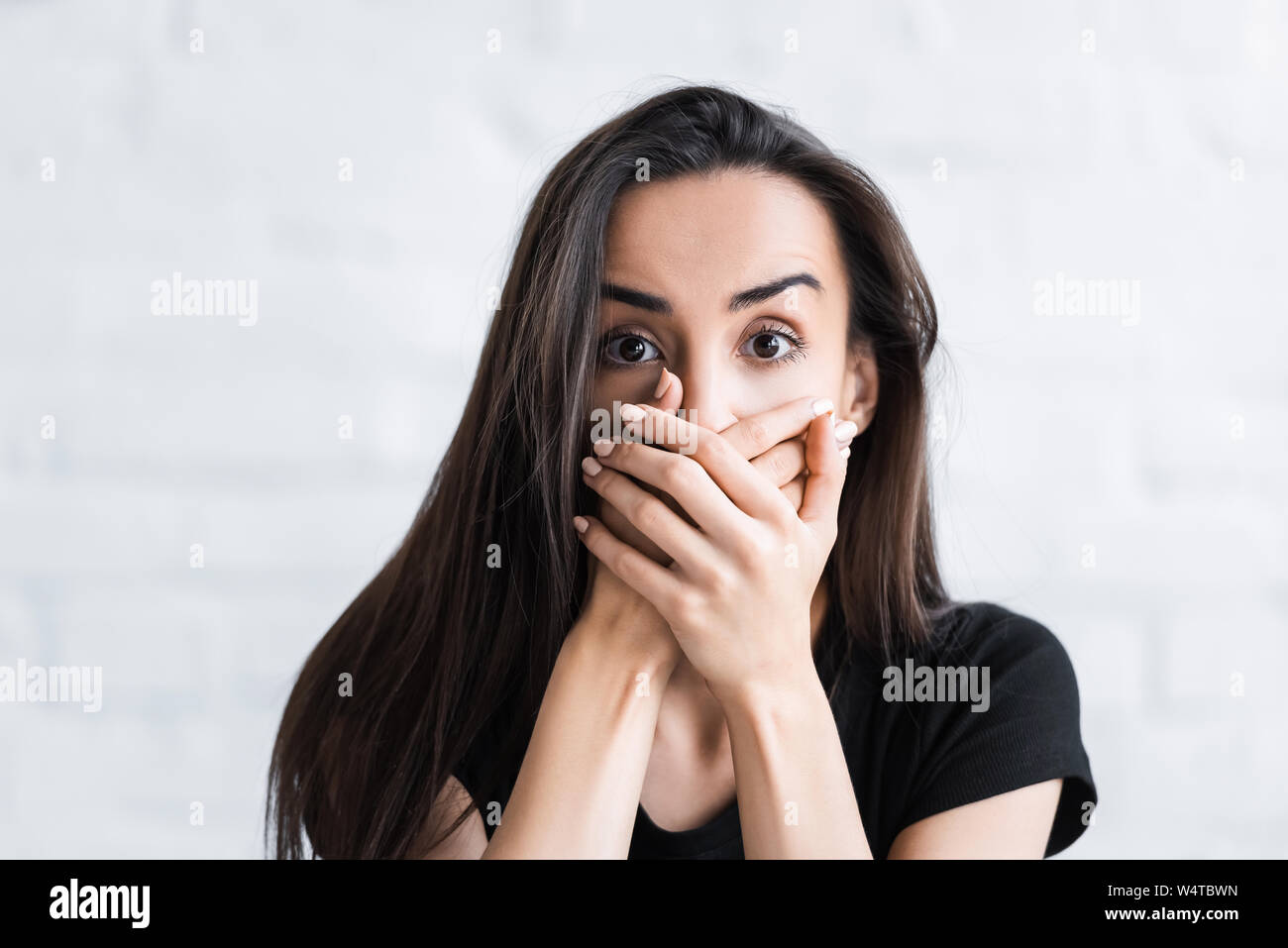 frightened young man looking at camera and covering face with hands ...