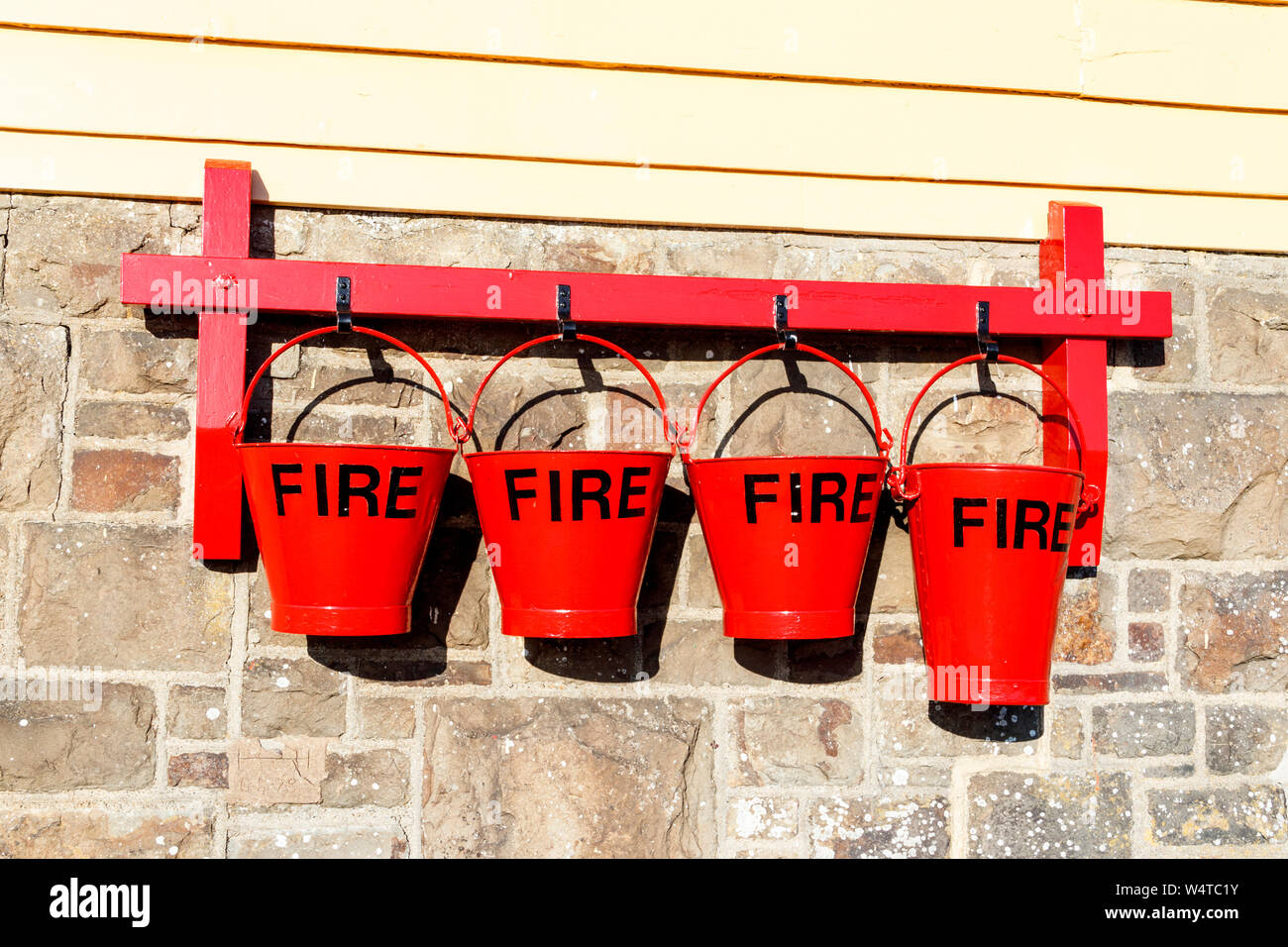 Four red fire buckets suspended from hooks on a disused railway signal ...
