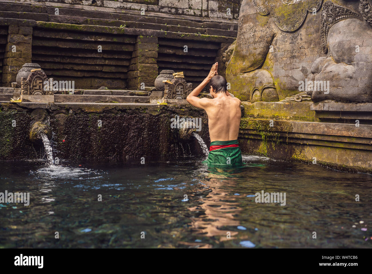Man in holy spring water temple in bali. The temple compound consists ...