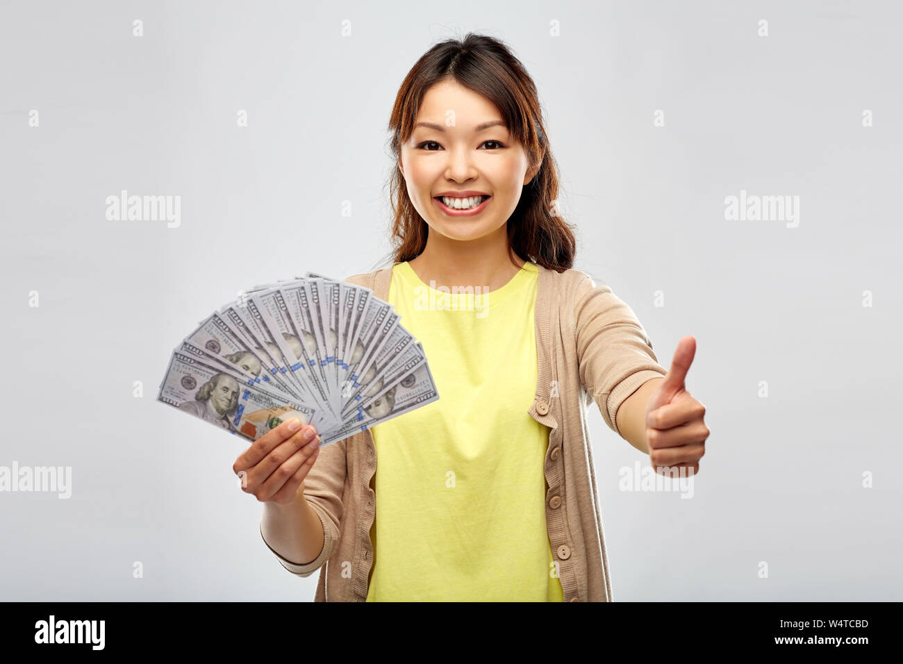 asian woman with dollar money showing thumbs Stock Photo - Alamy