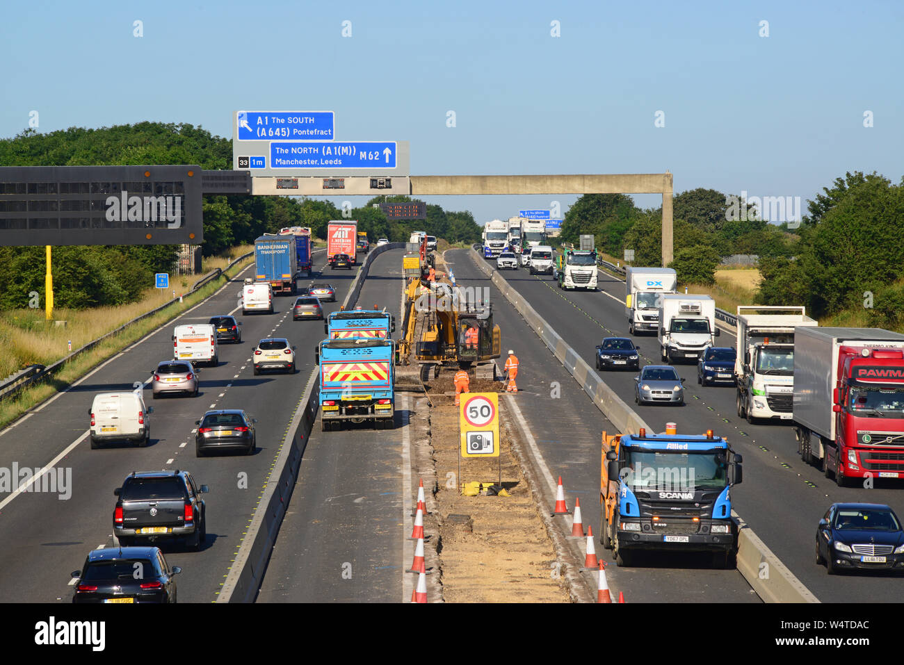 digger working in central reservation loading lorry's with rubble ...
