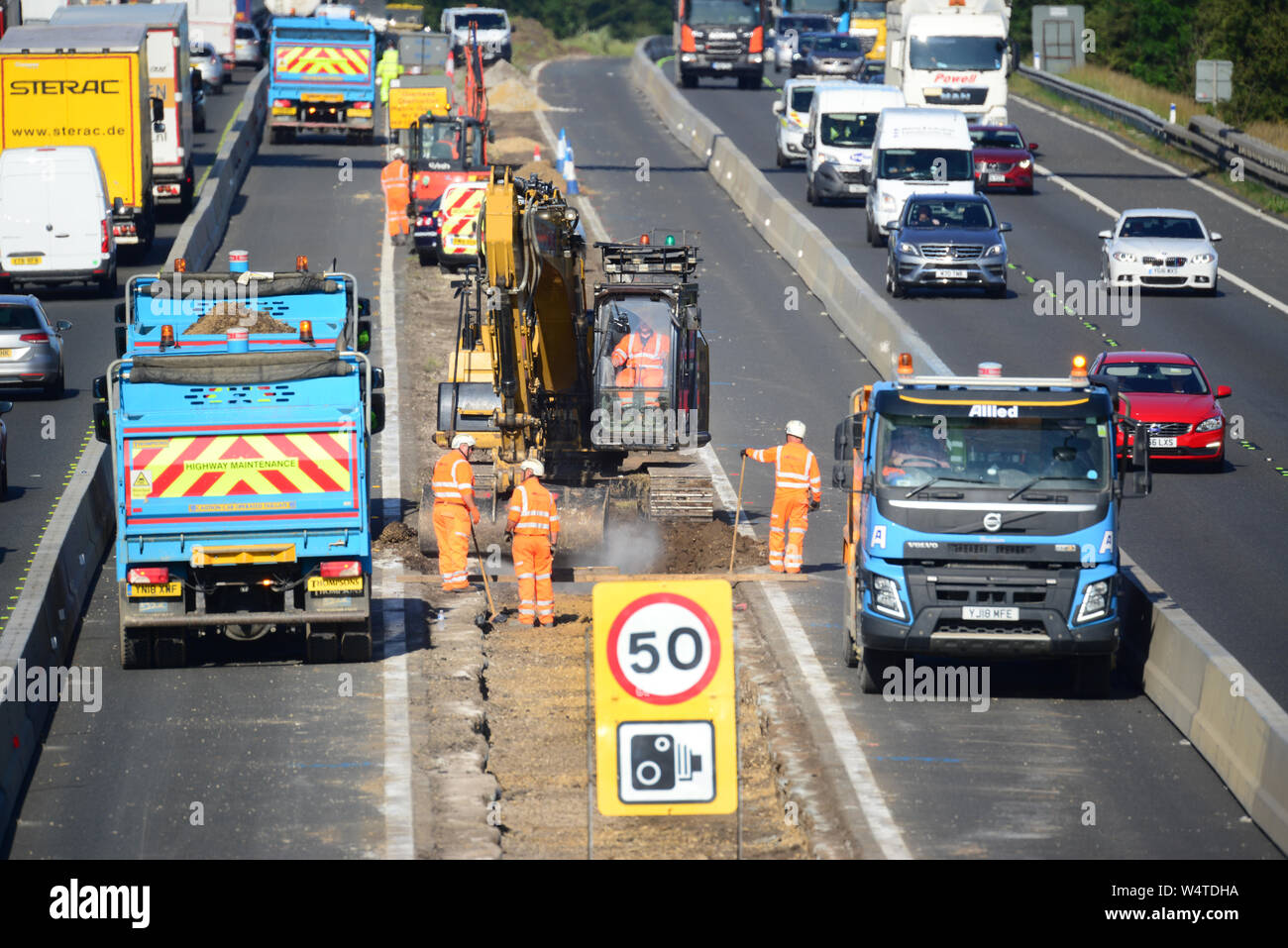 digger working in central reservation loading lorry's with rubble ...