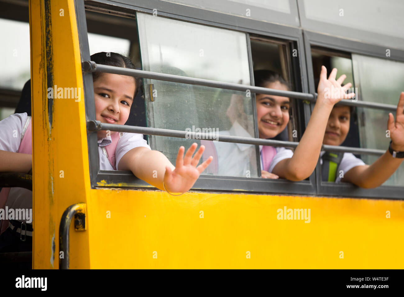 Happy school children waving hand from window of school bus Stock Photo ...